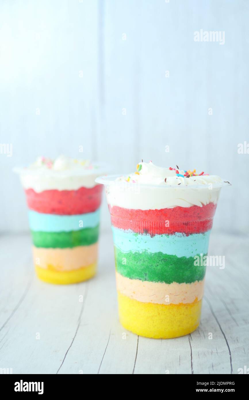 rainbow color cake in a plastic container on table Stock Photo - Alamy