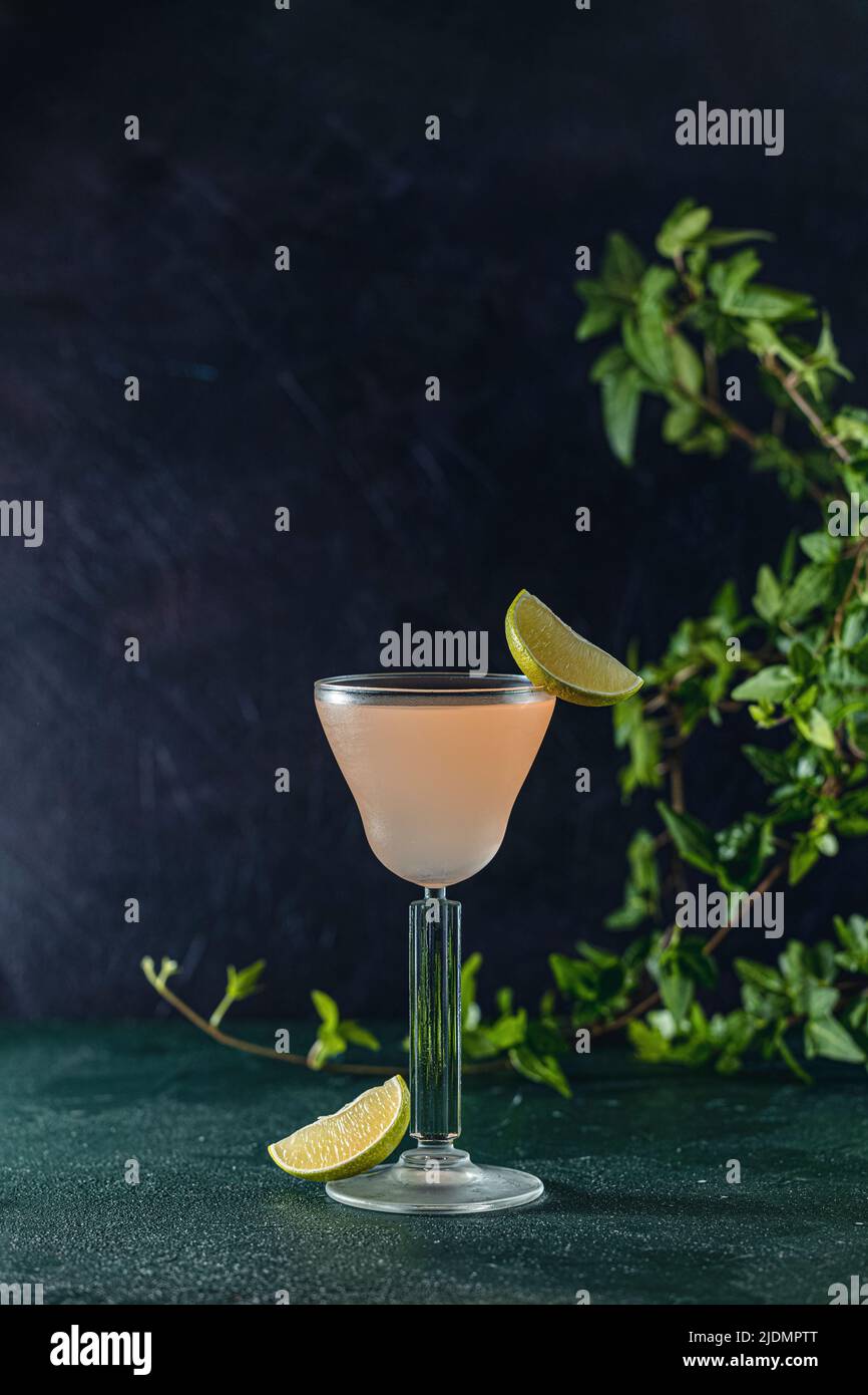 Glass of refreshing Pegu Club cocktail served on dark green table ...