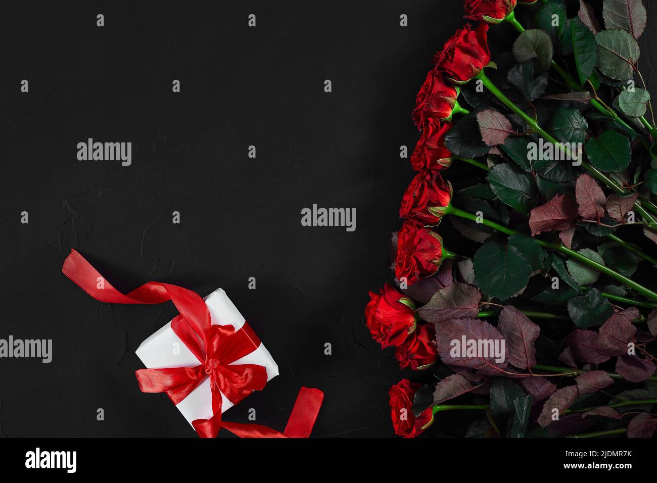 Red roses, ring and gift box on black background Stock Photo - Alamy