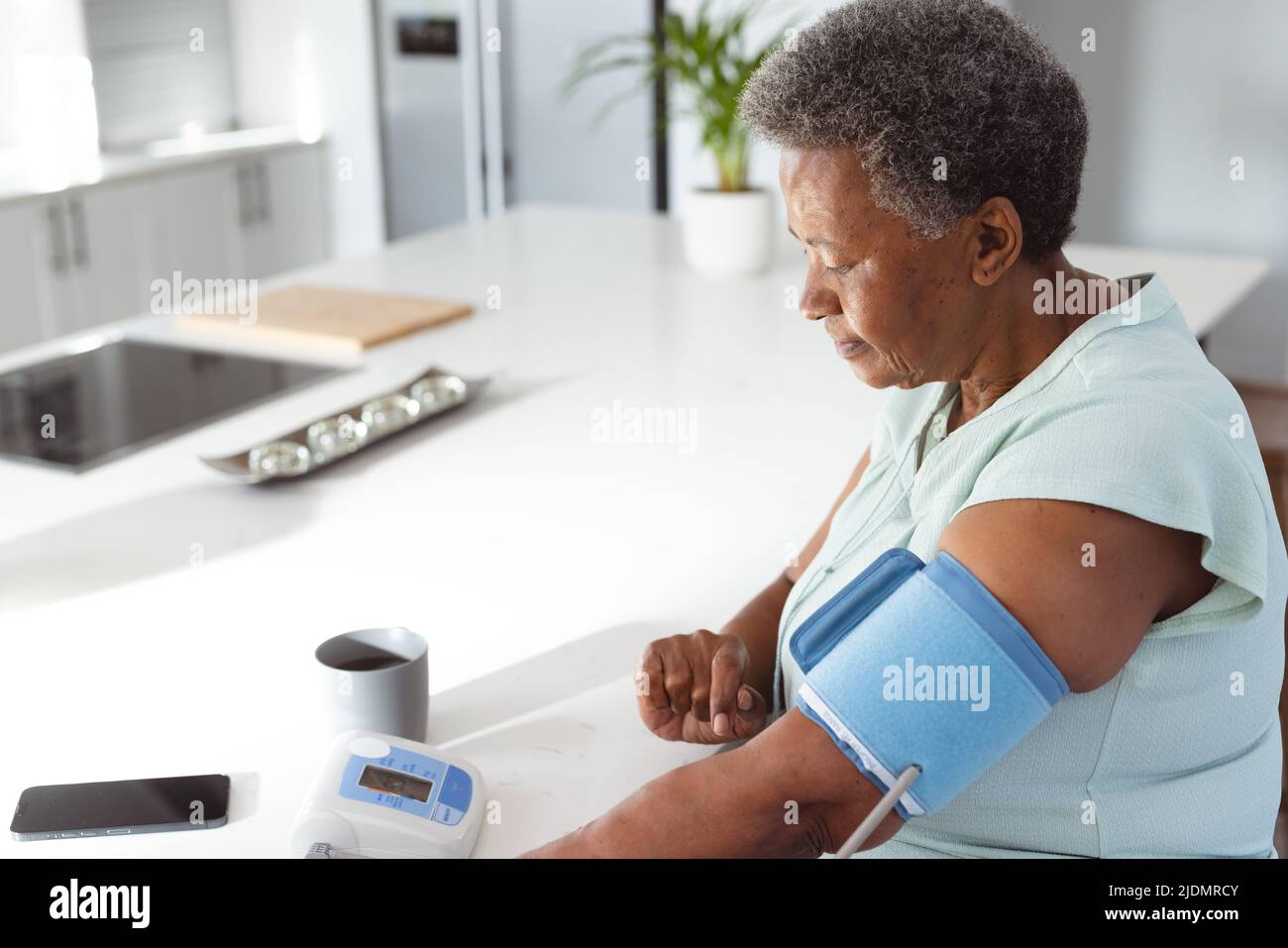 Side view of african american senior woman checking blood pressure with ...