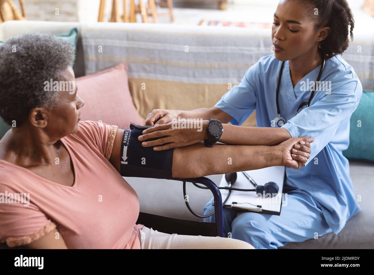 African american young doctor checking senior woman's blood pressure ...