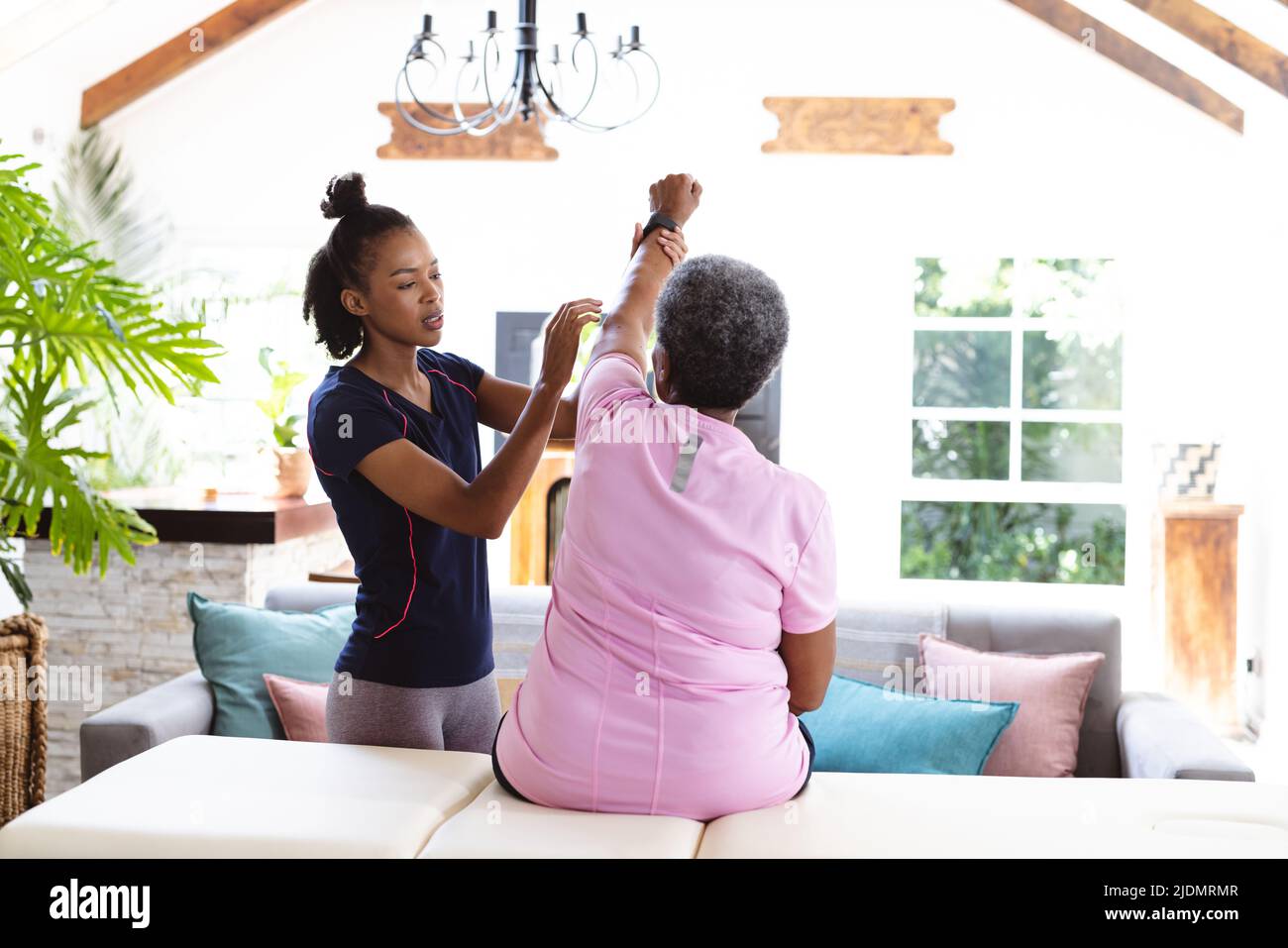 African american female physiotherapist stretching senior woman's hand ...