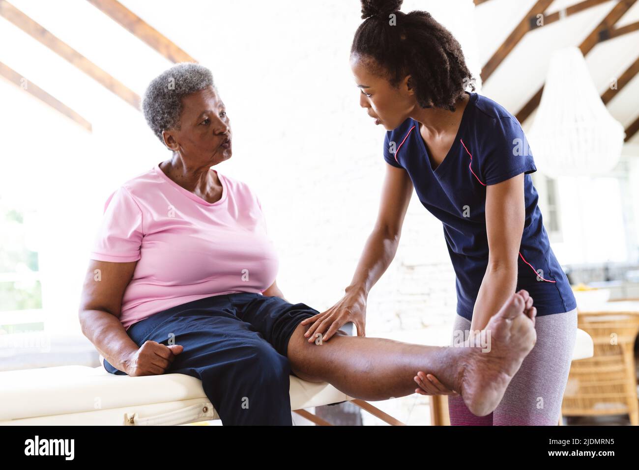 African american female physiotherapist stretching senior woman's leg ...