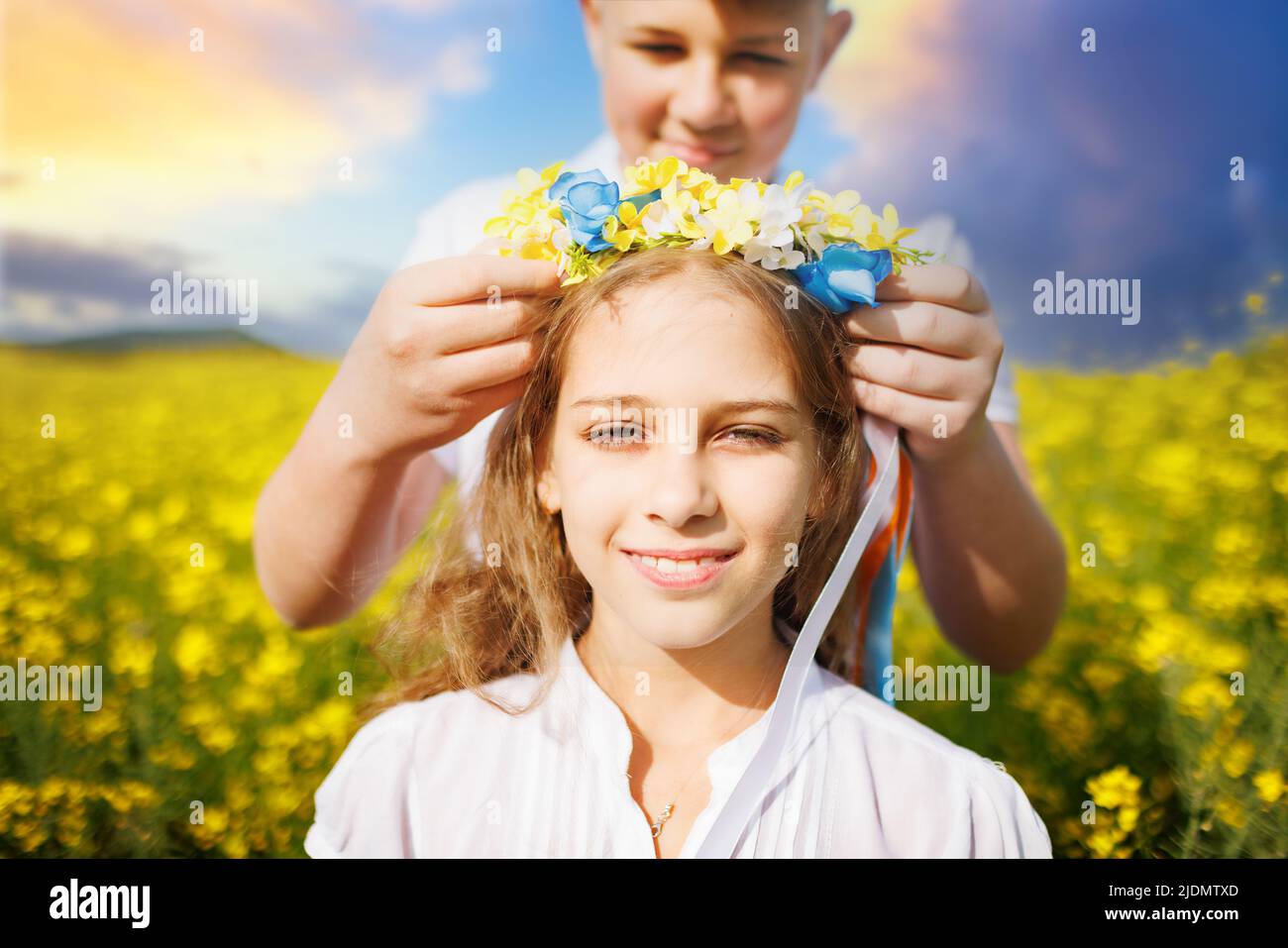 Kind caring teenage brother carefully puts on floral Ukrainian bright ...