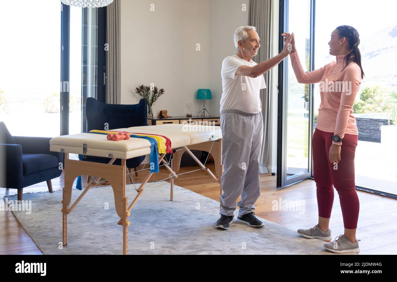 Happy caucasian senior man giving high-five to female biracial ...
