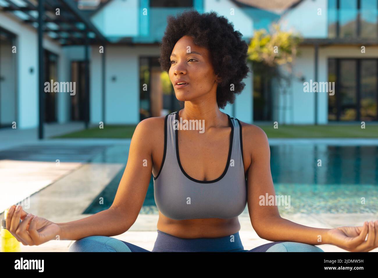 African american afro young woman looking away while practicing yoga on ...