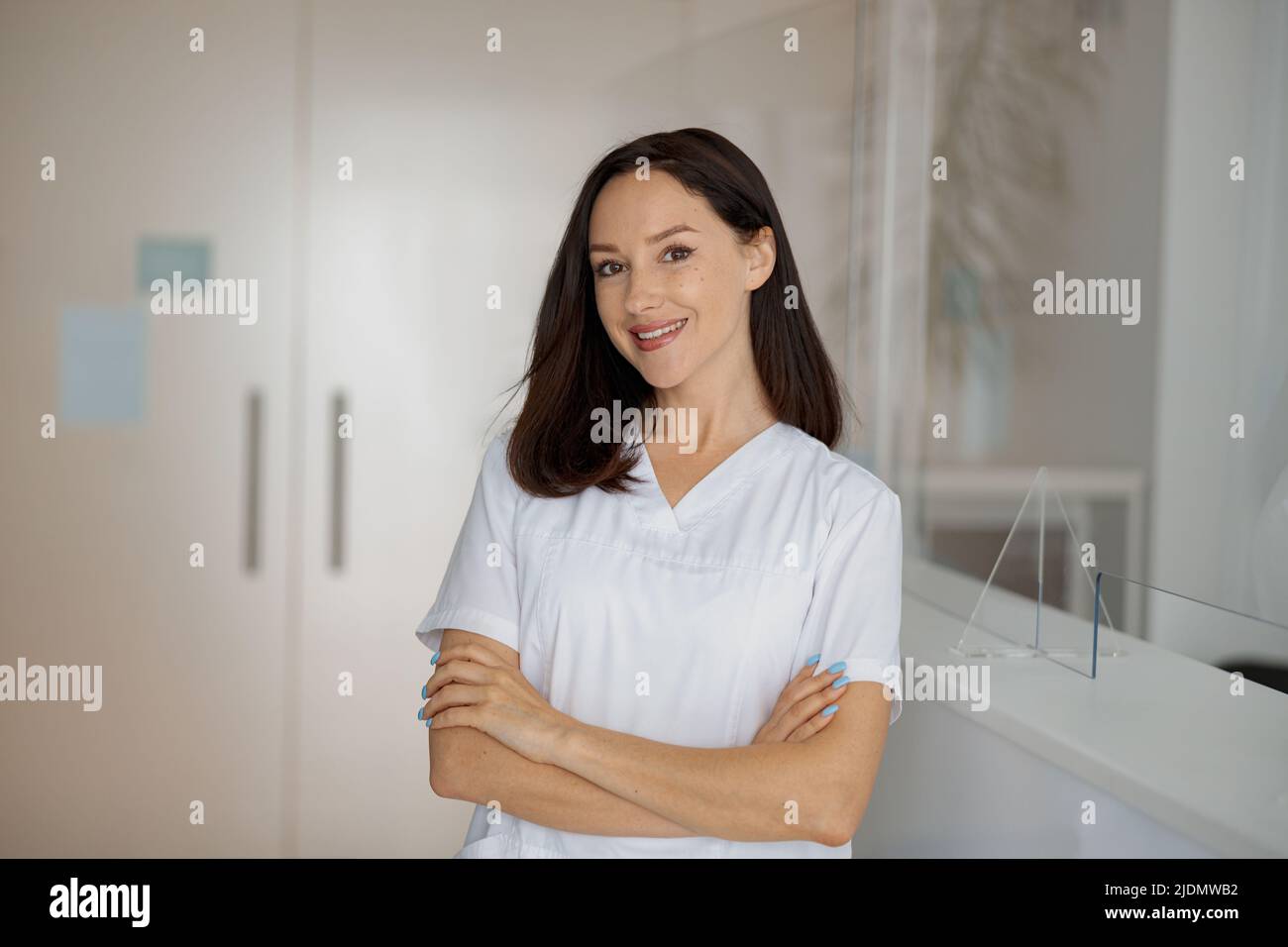Portrait of a smiling nurse standing near the reception in a medical ...