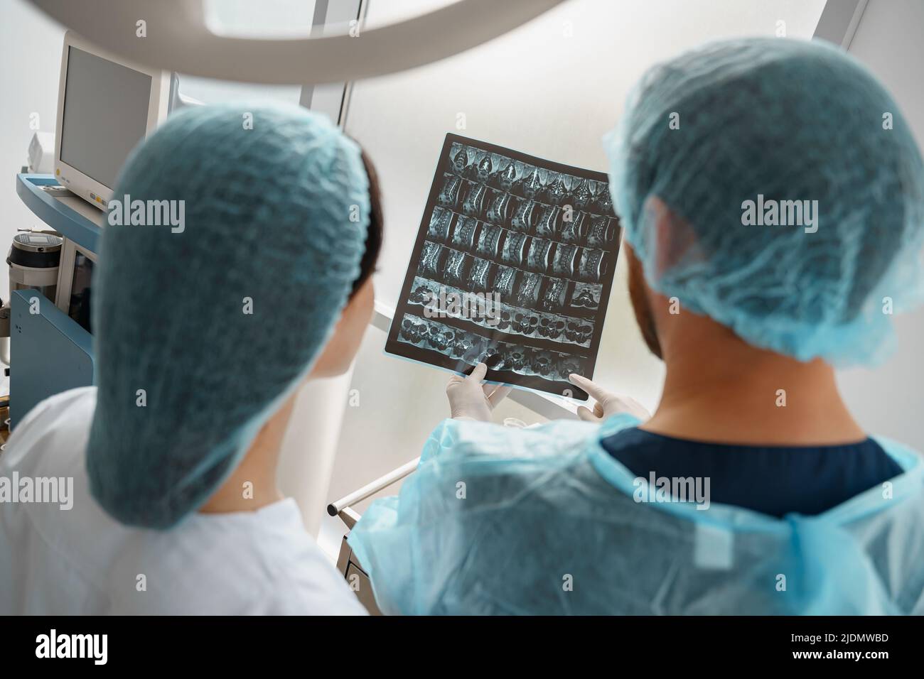 Doctor and nurse in uniform look and discuss an X-ray or MRI scan of ...