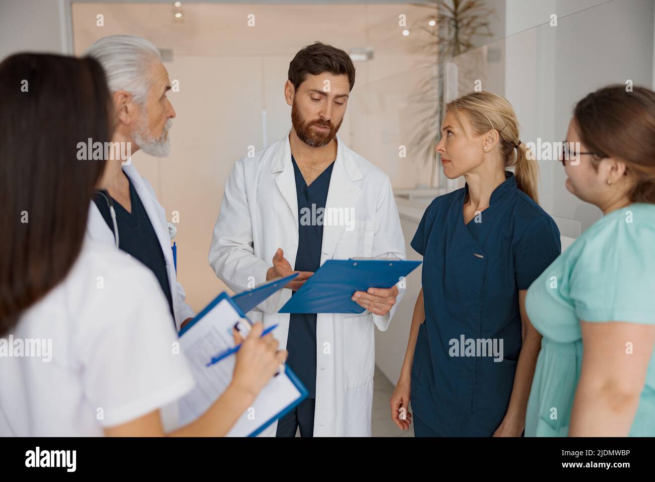 Group of doctor colleagues discussing patient diagnosis stand in clinic ...