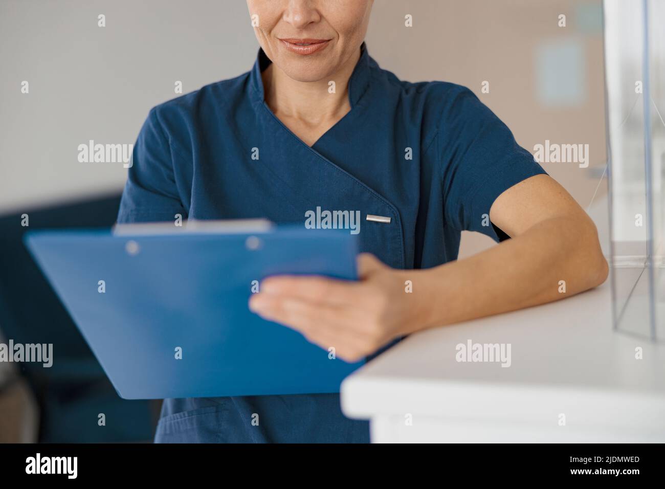 Close up doctor making notes on clipboard standing near reception in ...