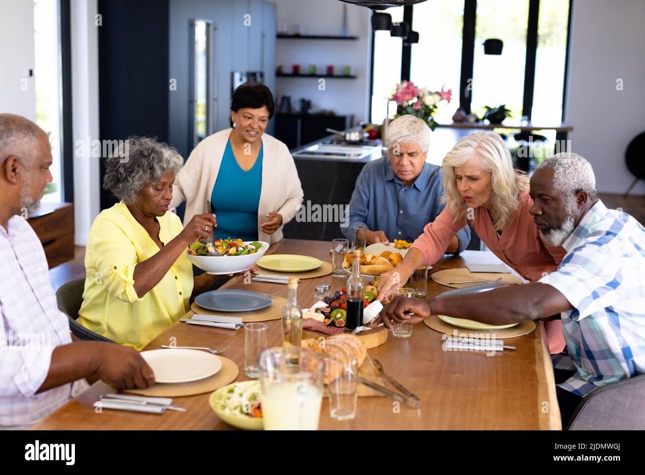 Multiracial senior friends having lunch on dining table at nursing home ...