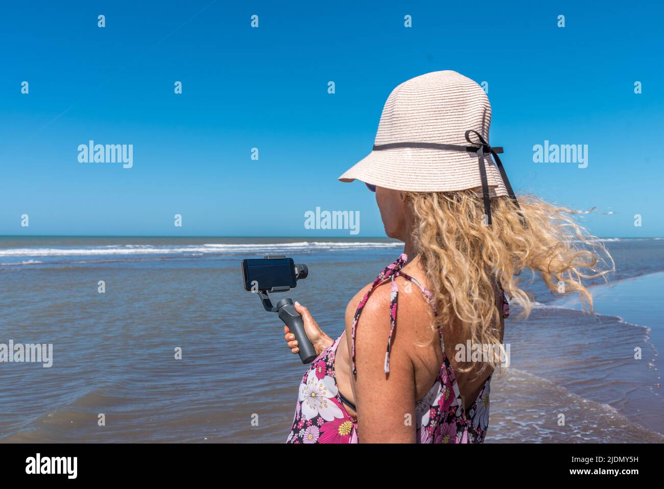 Woman using a mobile phone with a tripod while the wind moves her hair ...
