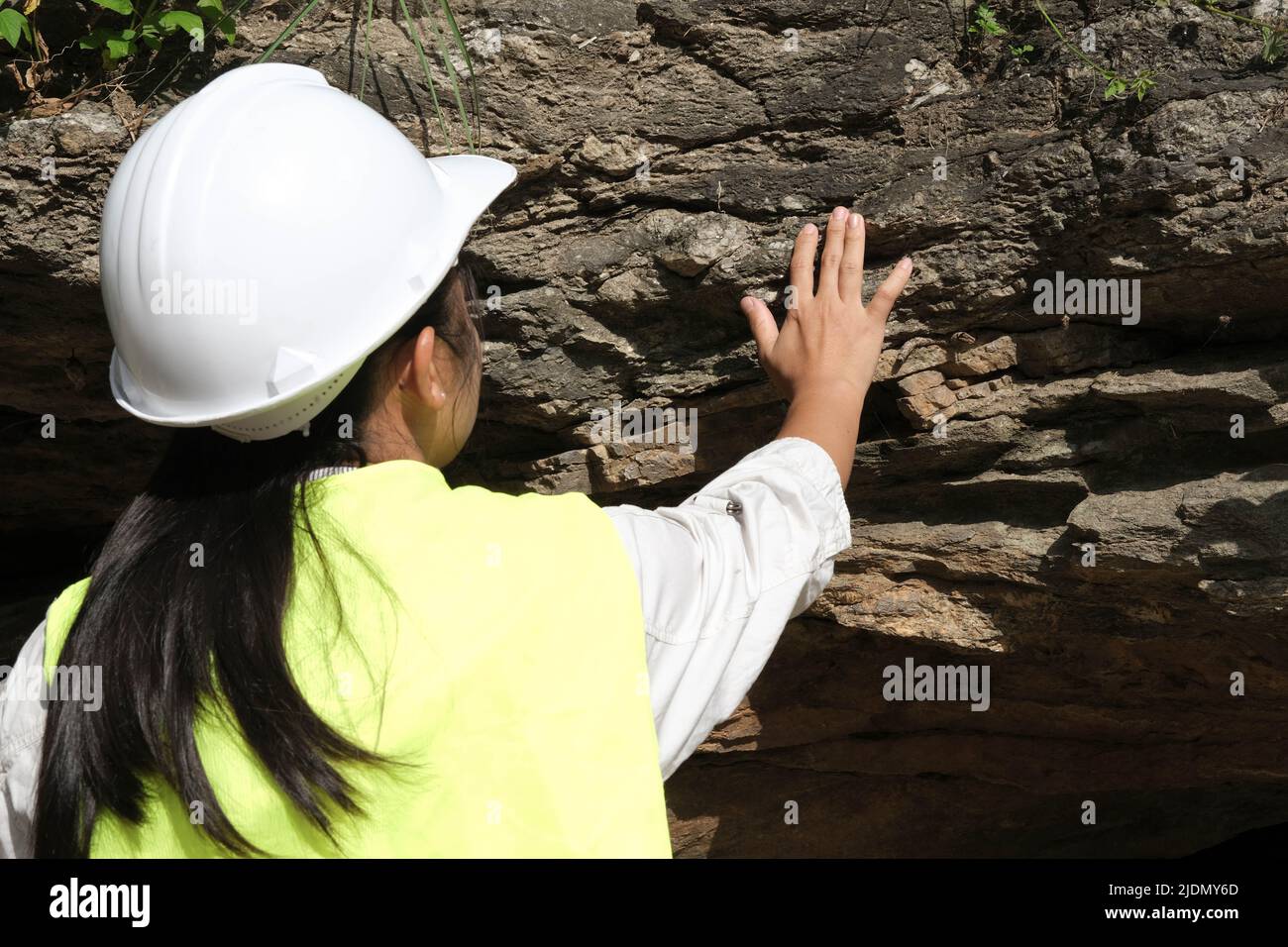 Asian female geologist researcher touches rocks with her hands to ...