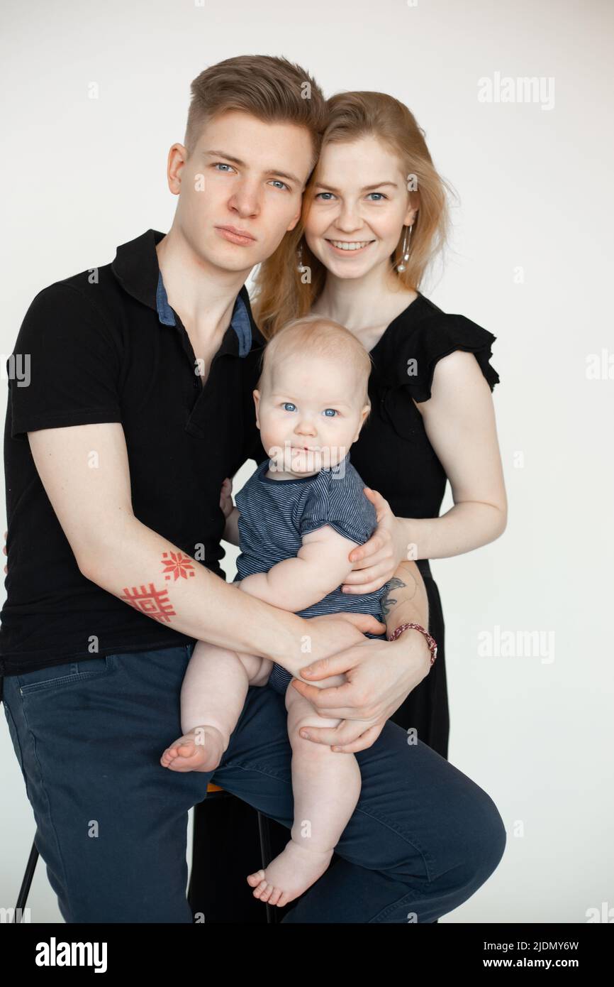 Portrait of young good-looking family in dark clothes with plump ...