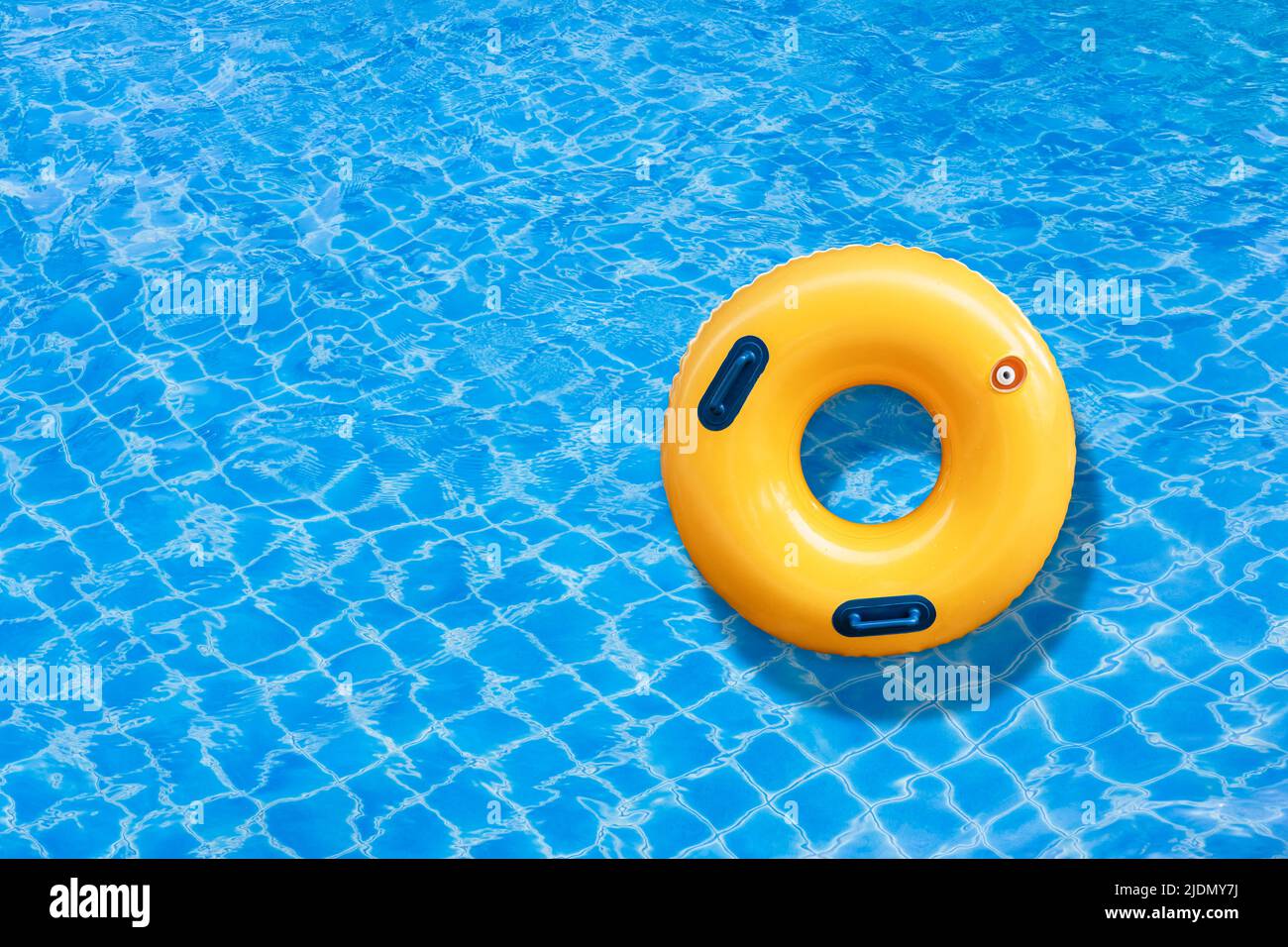 Yellow ring floating in a blue wave water on the outdoor swimming pool ...