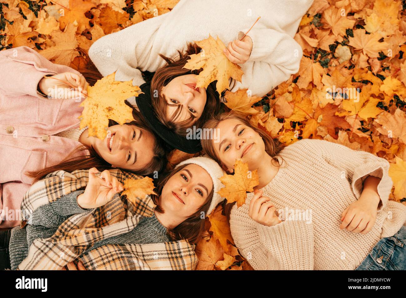 Autumn portrait of Happy four young women students playing with leaves ...