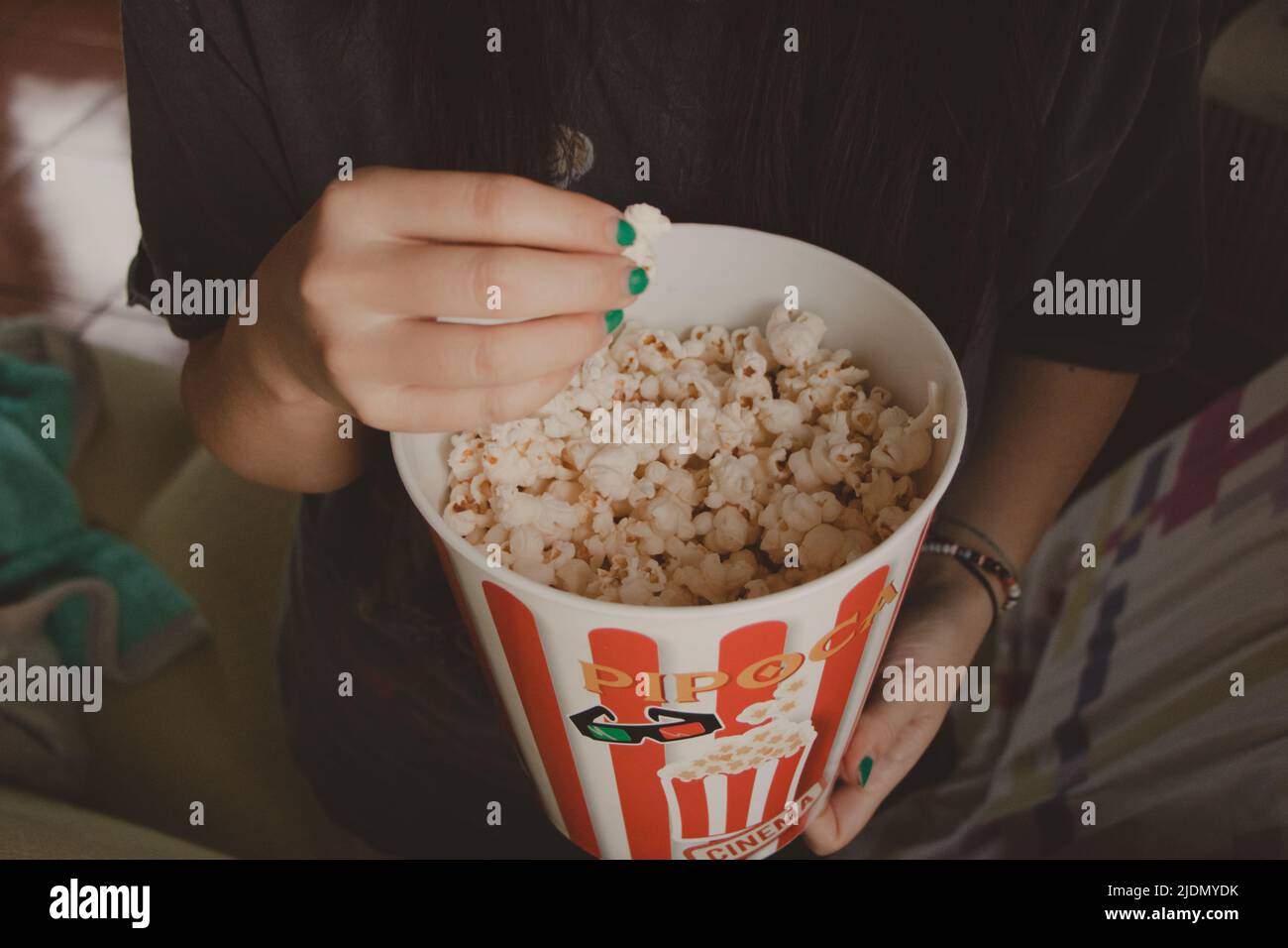 young woman eating popcorn on a bucket Stock Photo - Alamy