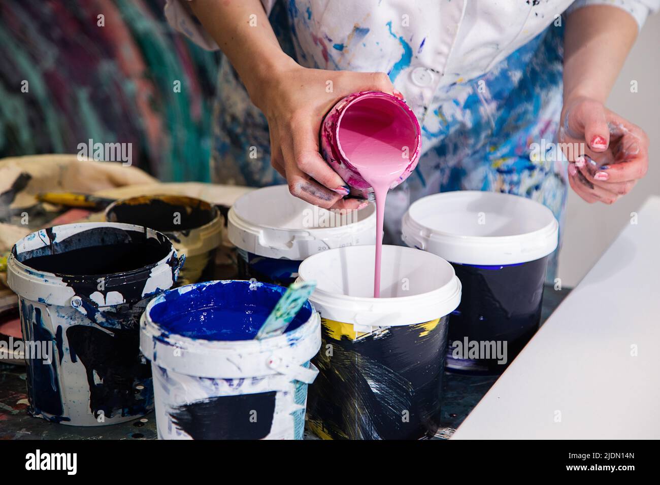 Close up of painter hands pouring paint from jar into can wearing white ...