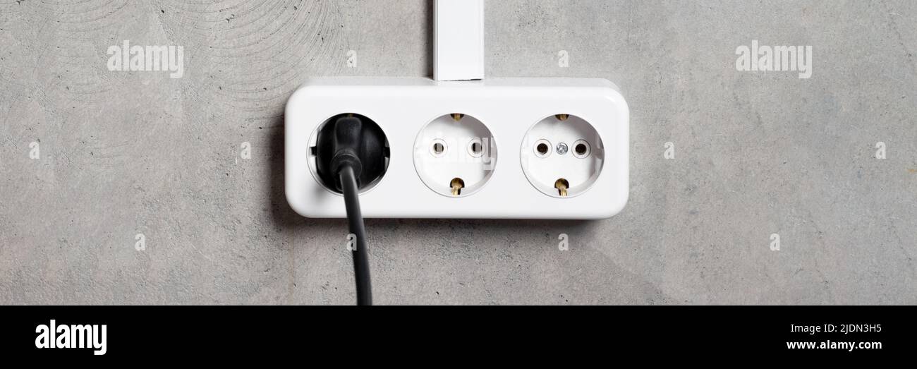 Group of white european electrical outlets with plug on gray concrete ...