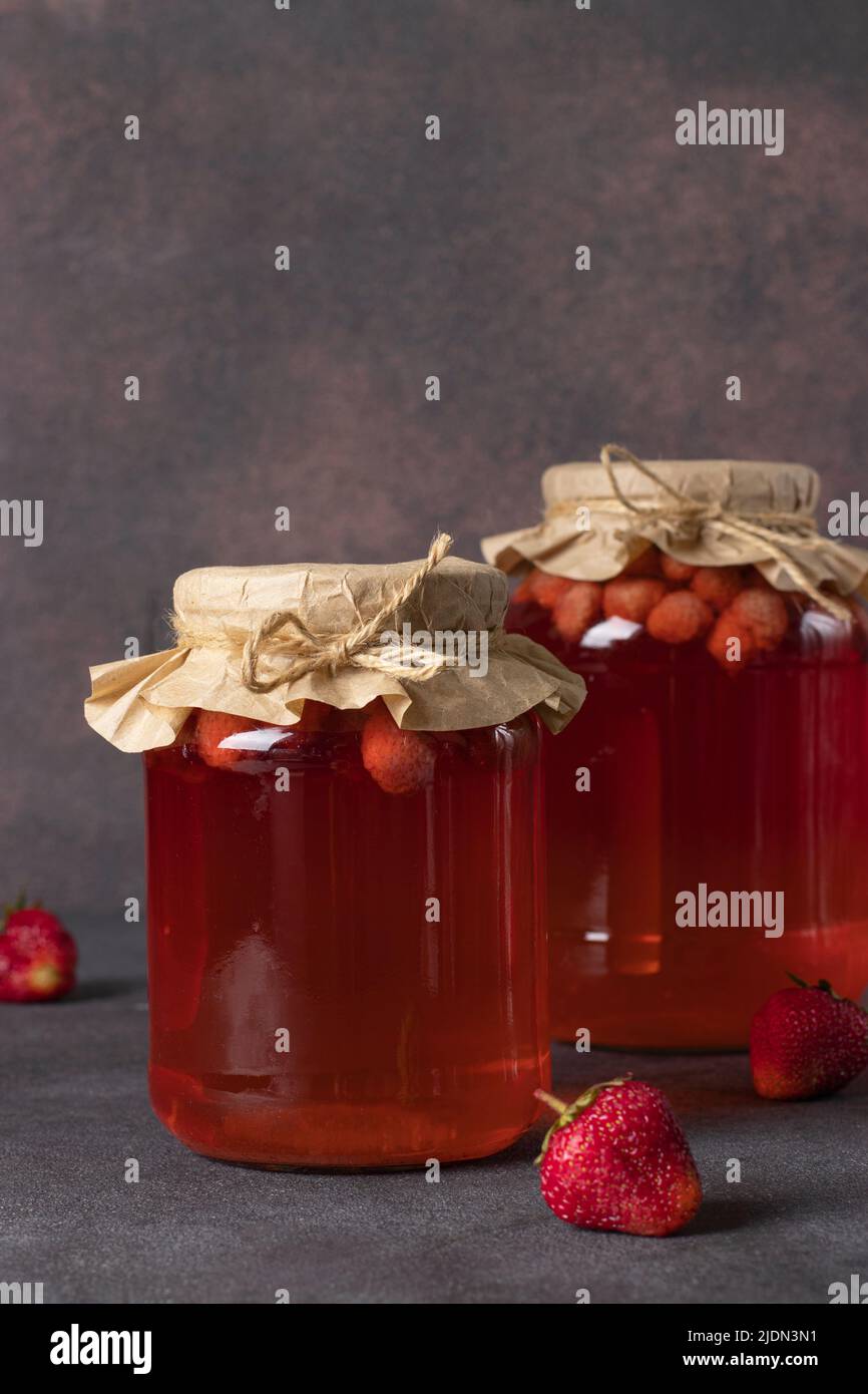 Homemade canned compote with strawberries in two jars on brown ...