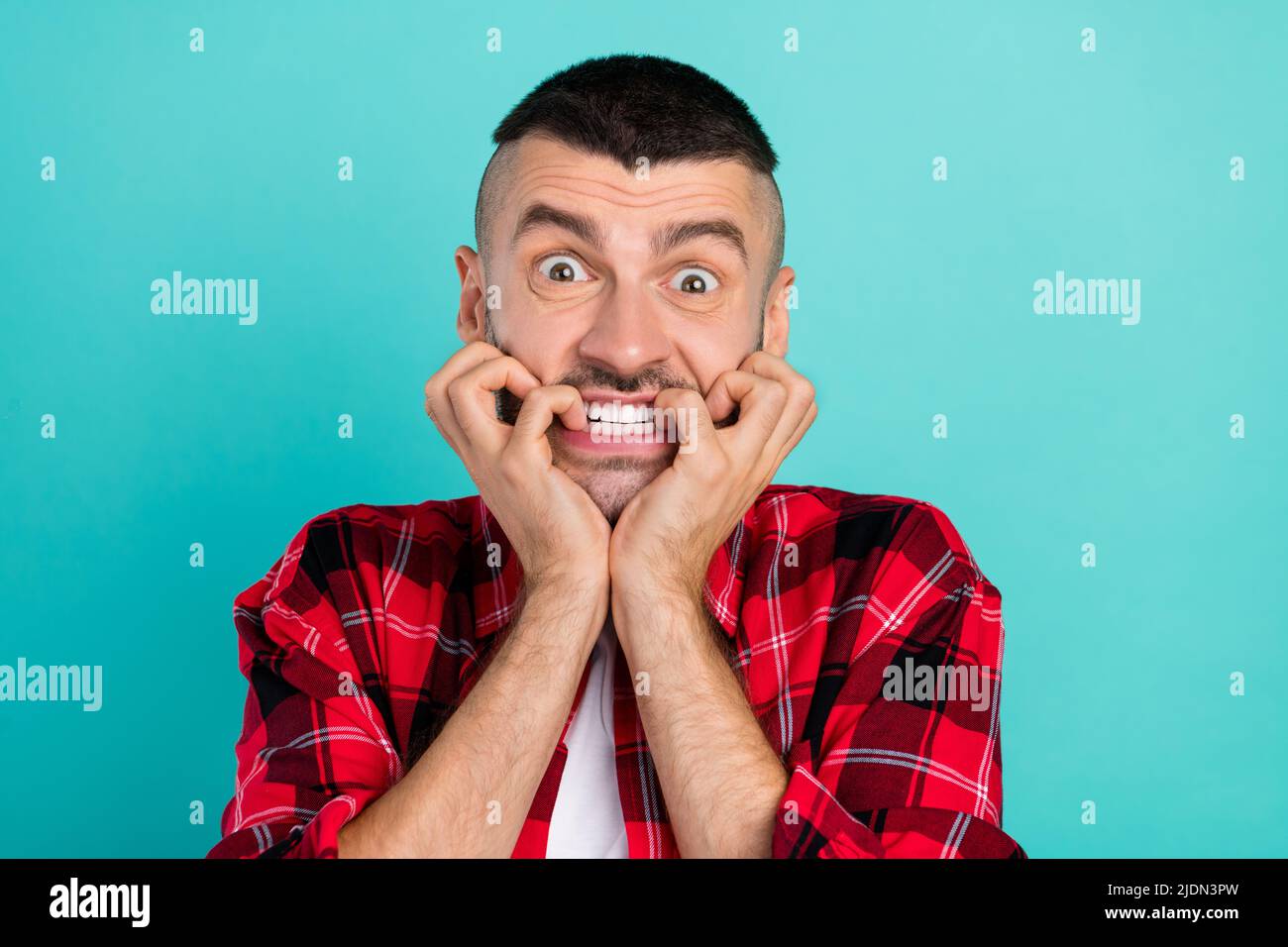 Photo of scared young brunet guy bite hands wear red shirt isolated on ...