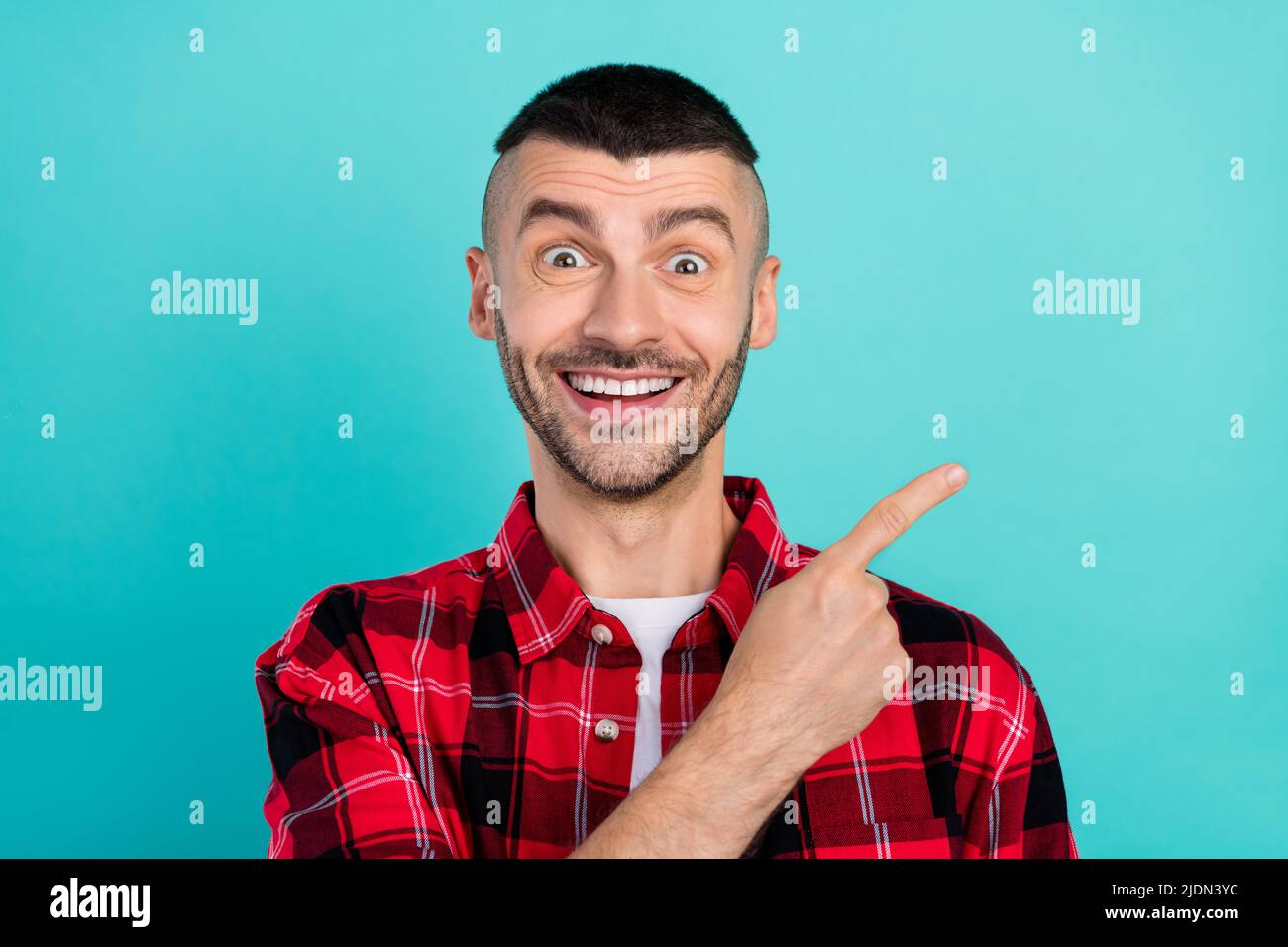 Photo of impressed millennial brunet guy point empty space wear red ...