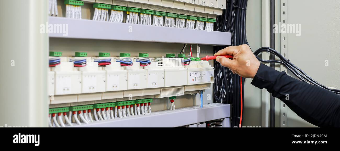 Electrical engineers check electrical control devices with a multimeter ...