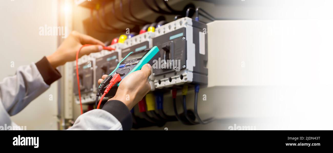Electrical engineers check electrical control devices with a multimeter ...
