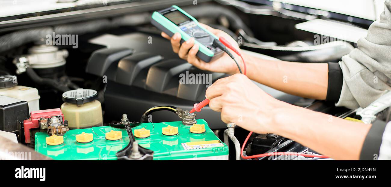 A technician is checking the car battery for availability Stock Photo ...