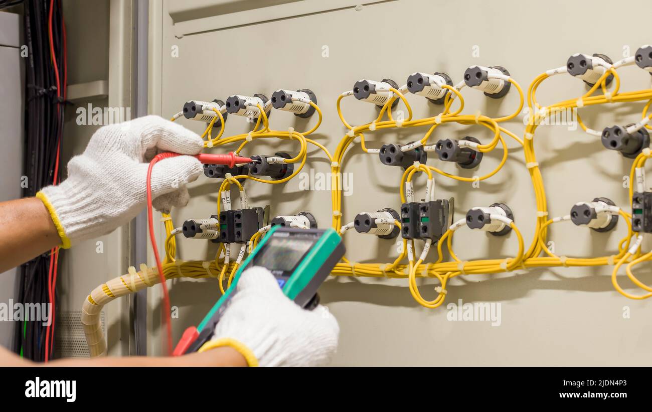 Electrical engineers check electrical control devices with a multimeter ...