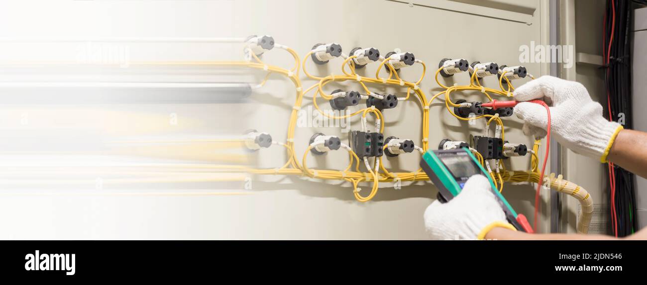 Electrical engineers check electrical control devices with a multimeter ...