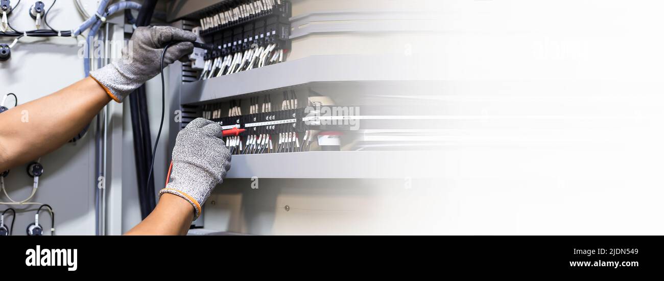 Electrical engineers check electrical control devices with a multimeter ...