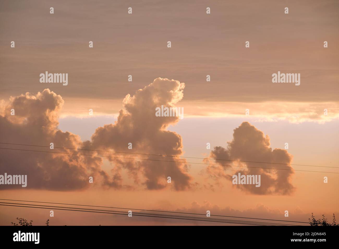 Bright colorful sunset sky with vivid smooth clouds illuminated with setting sun light spreading ...