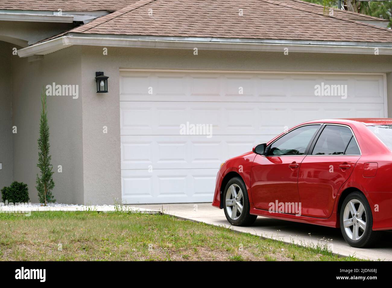 Car parked in front of wide garage double door on concrete driveway of ...