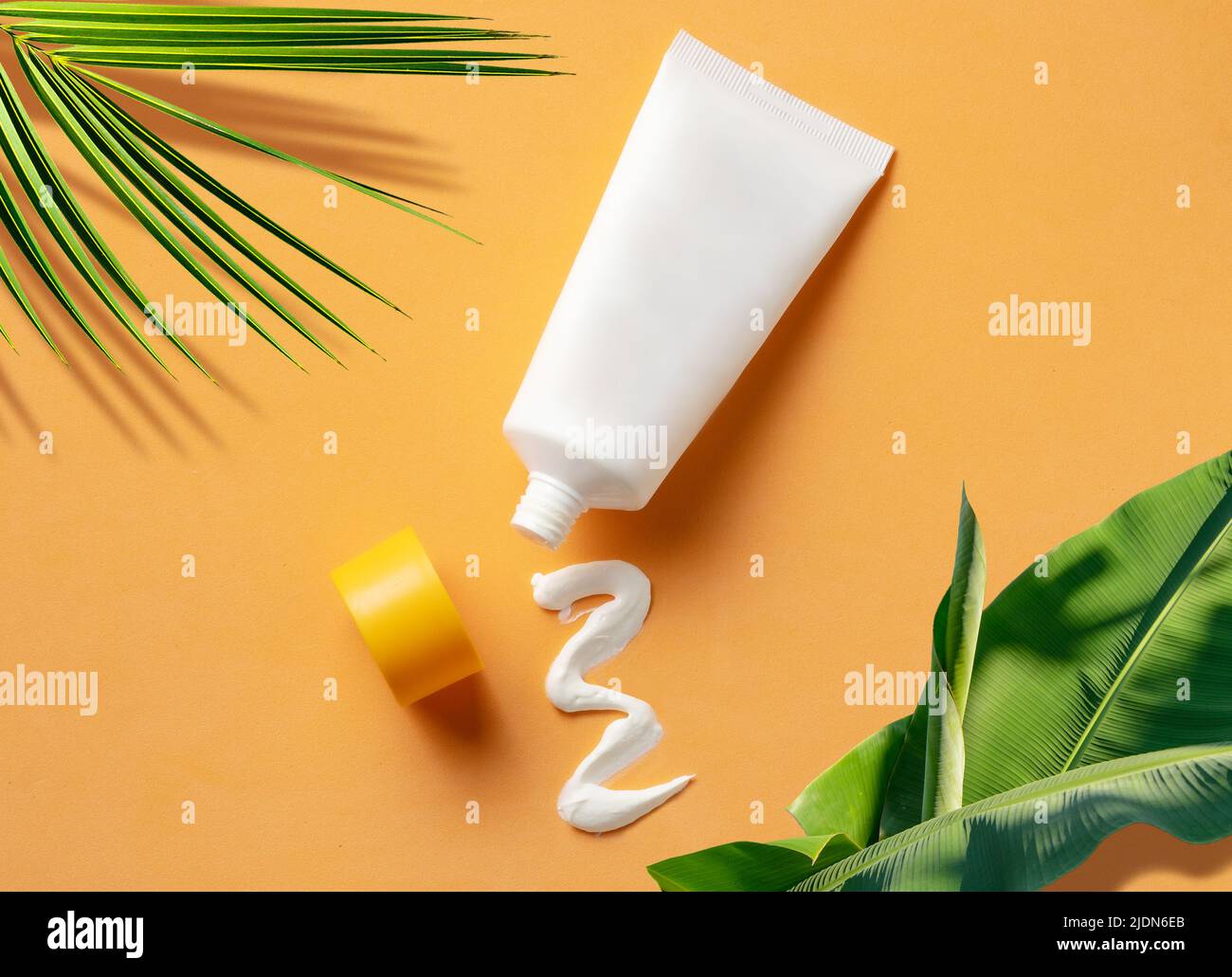 White cosmetic tube with sunscreen cream and squeezed cream texture on ...