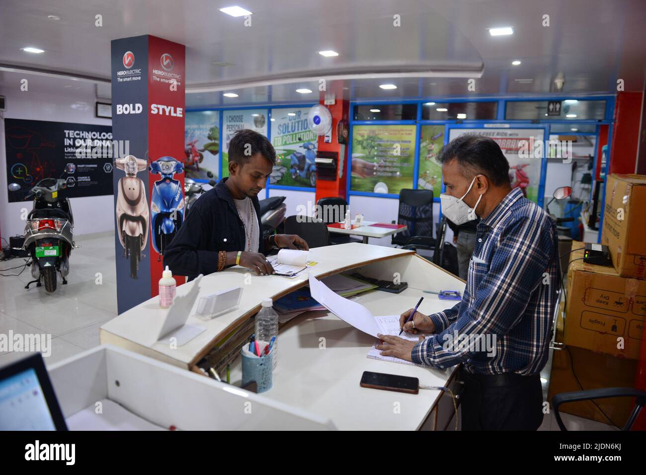 Young Indian customer takes information about an electric two-wheeler ...