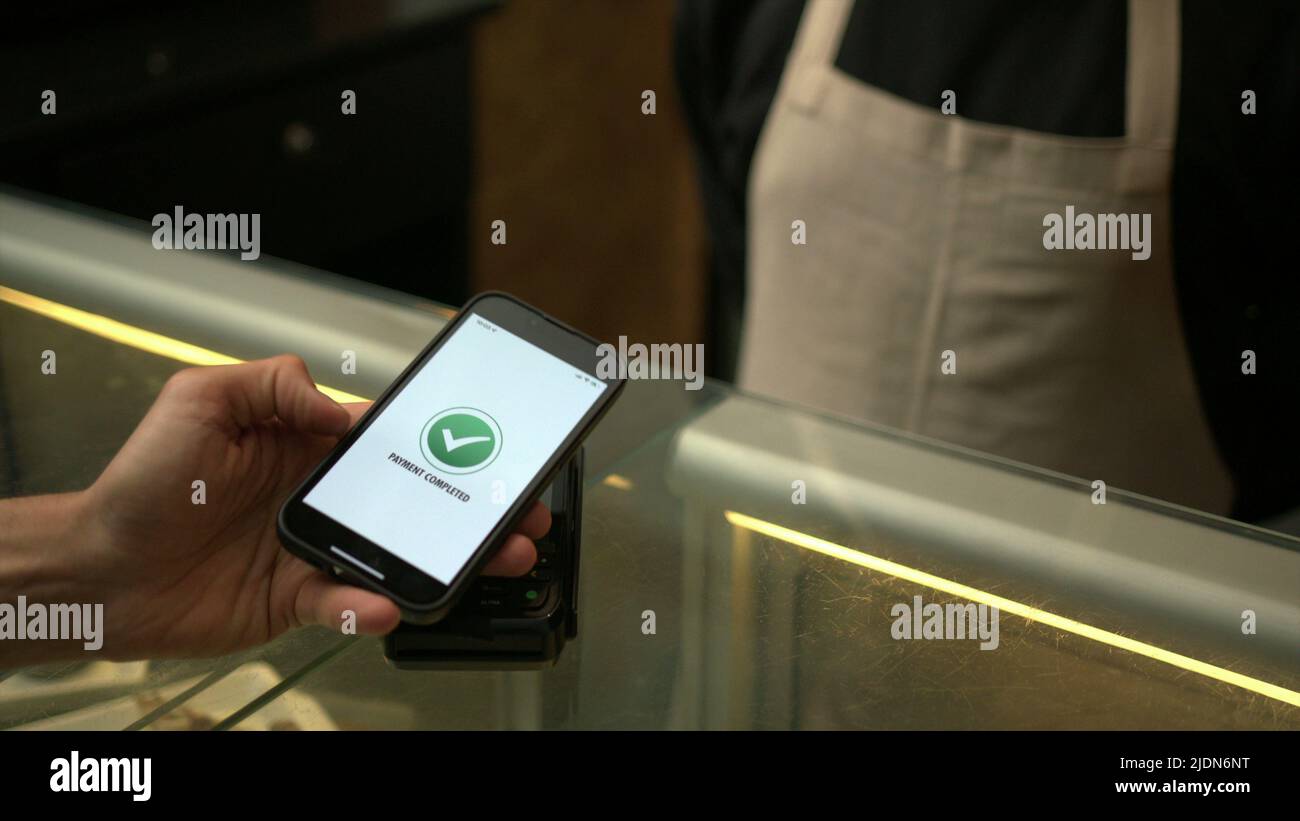 Customer paying with contactless NFC payment technology on smartphone ...