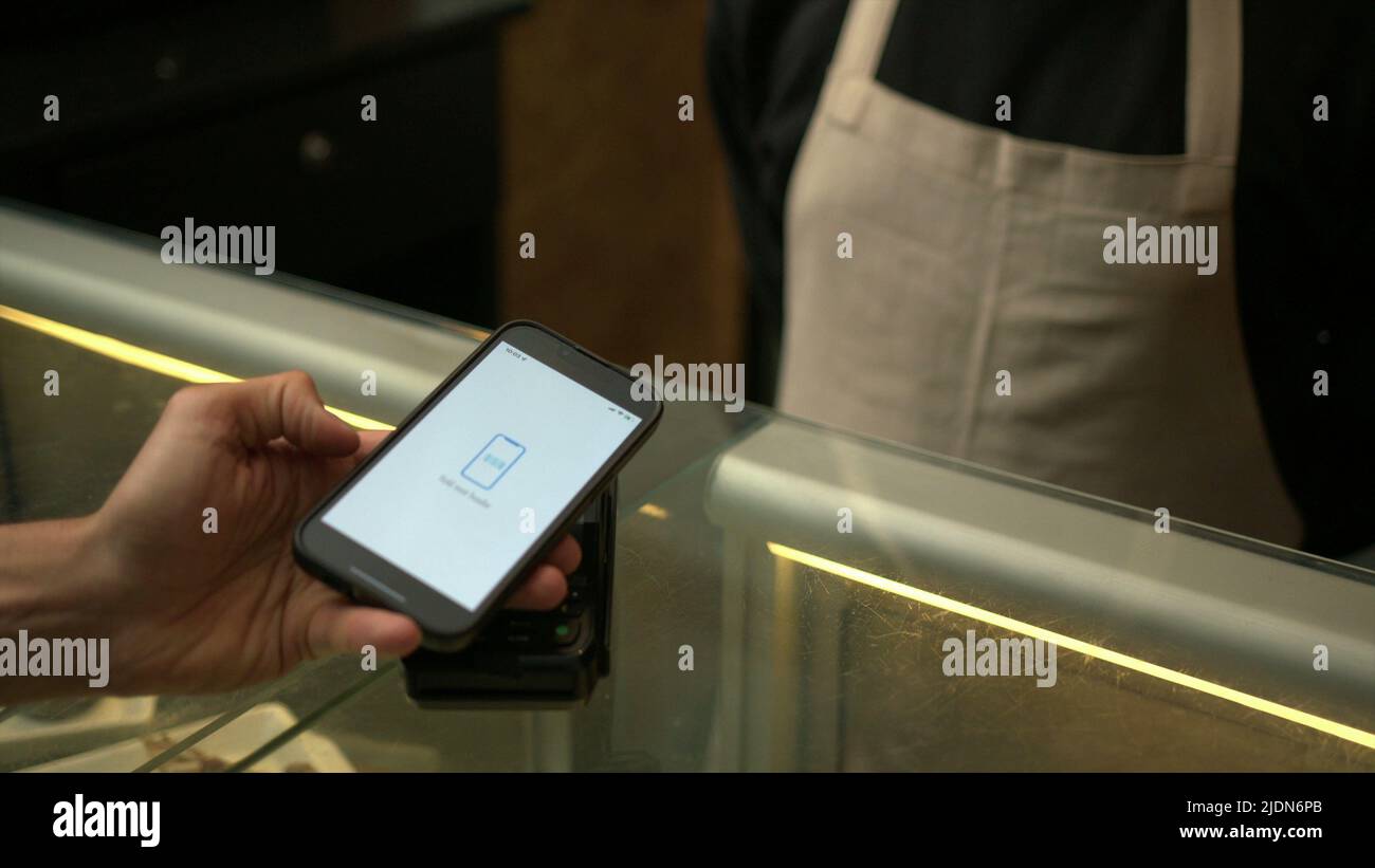 Customer paying with contactless NFC payment technology on smartphone ...
