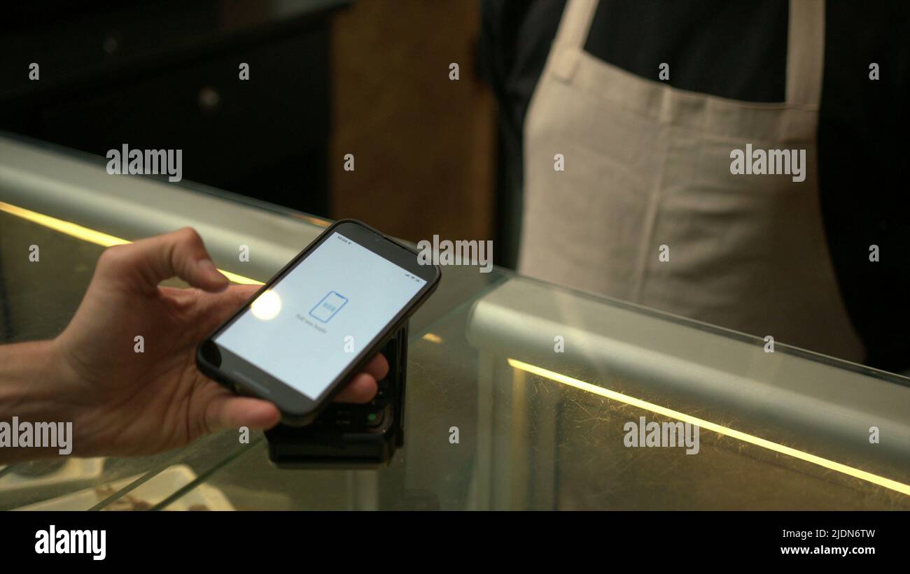 Customer paying with contactless NFC payment technology on smartphone ...
