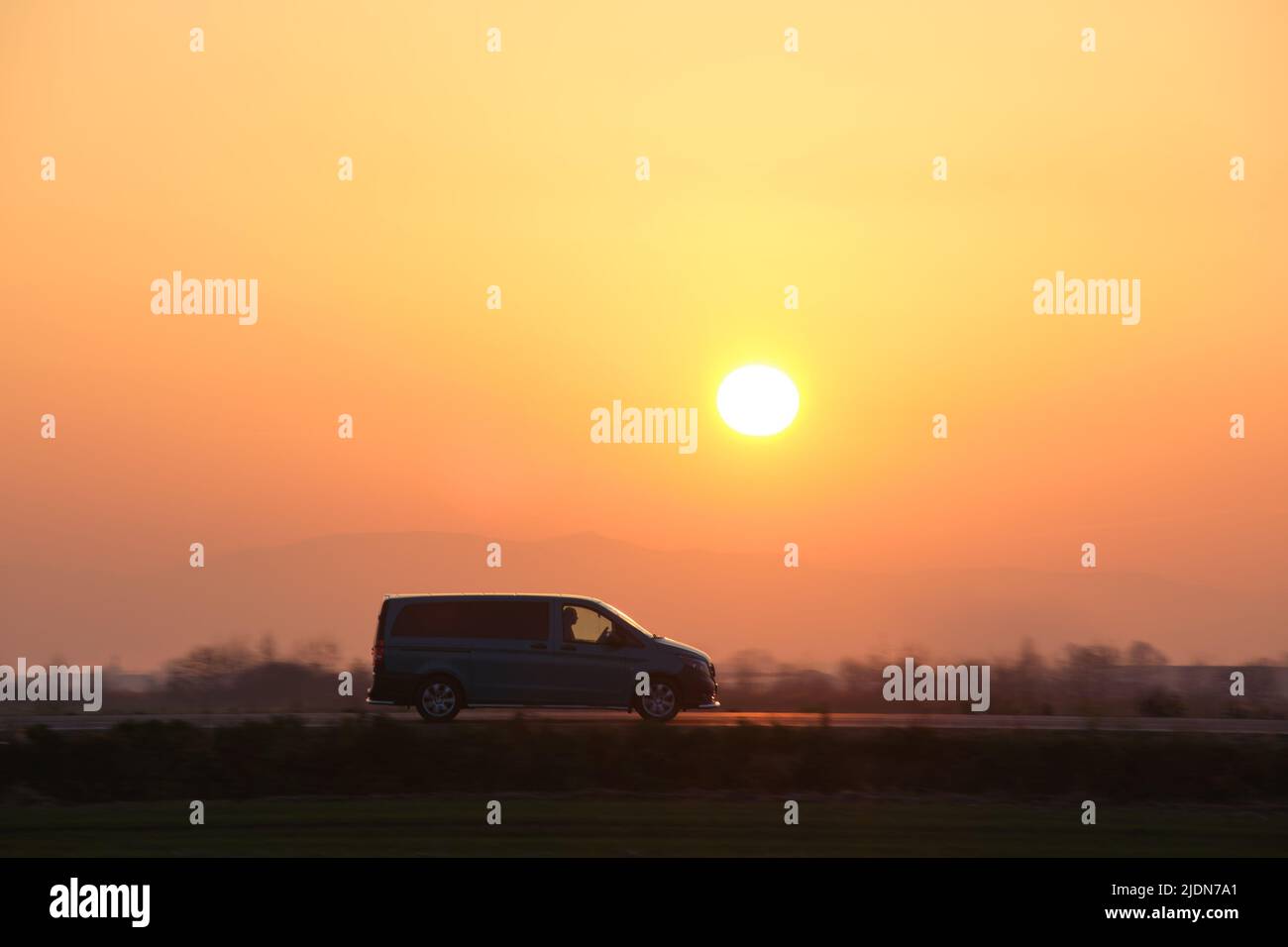 Passenger van driving fast on intercity road at sunset. Highway traffic ...