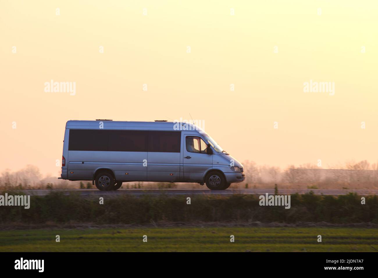 Passenger van driving fast on intercity road at sunset. Highway traffic ...