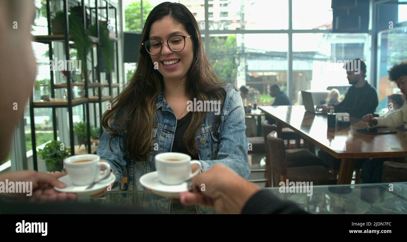 Female customer picking up coffee order inside coffee shop counter ...