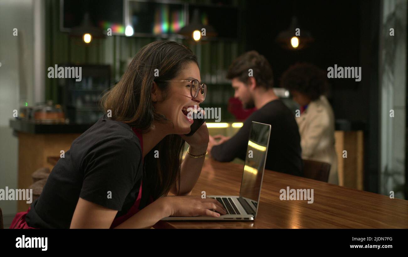 Happy girl staff talking on phone smiling and laughing browsing online ...