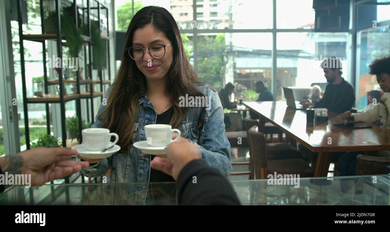Female customer picking up coffee order inside coffee shop counter ...