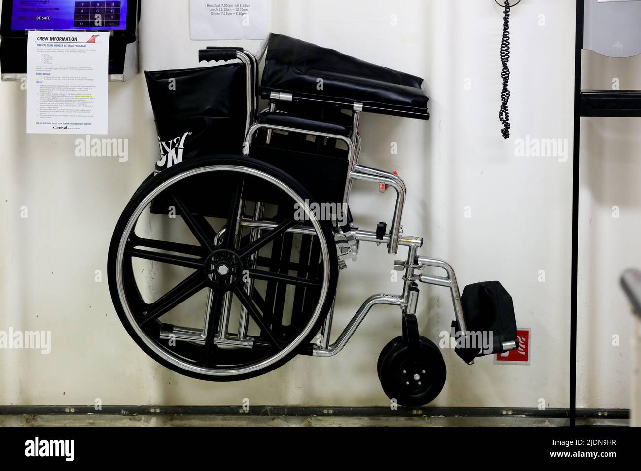 wheelchair hanging on a wall in a crew area for emergency case and a ...