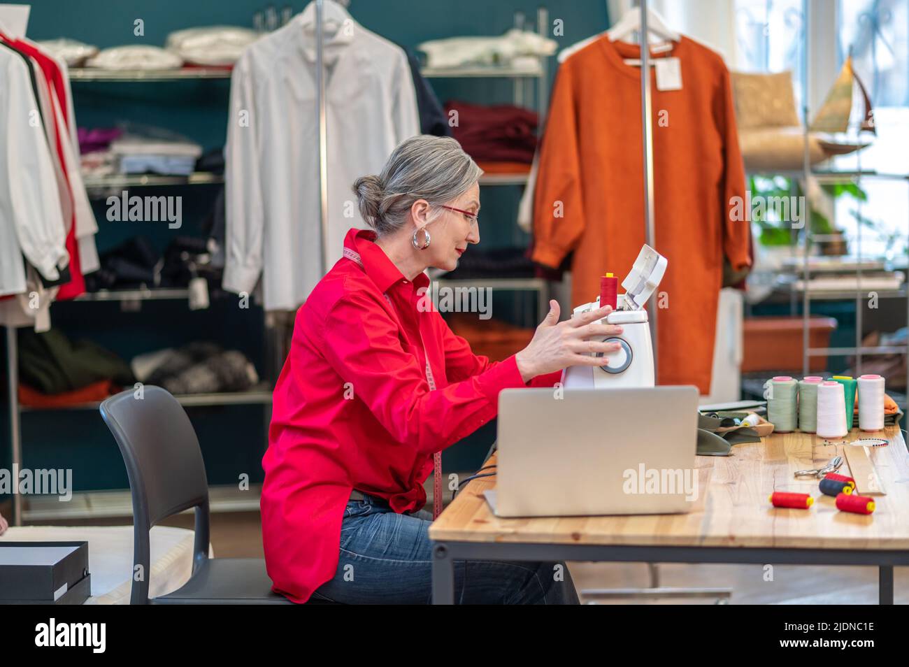 Woman touching sewing machine sitting sideways to camera Stock Photo ...