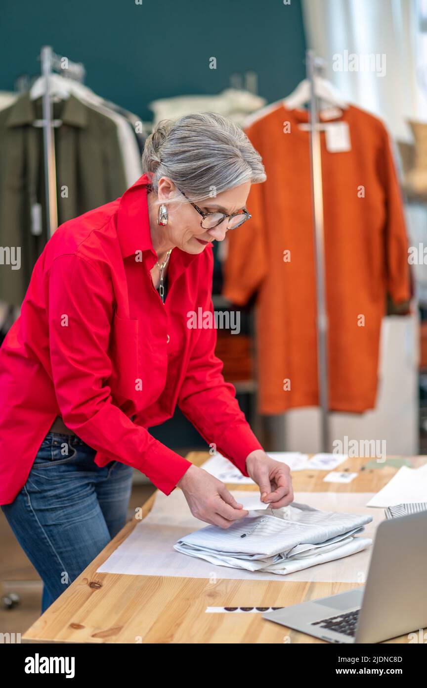 Woman touching clothes standing near table Stock Photo - Alamy
