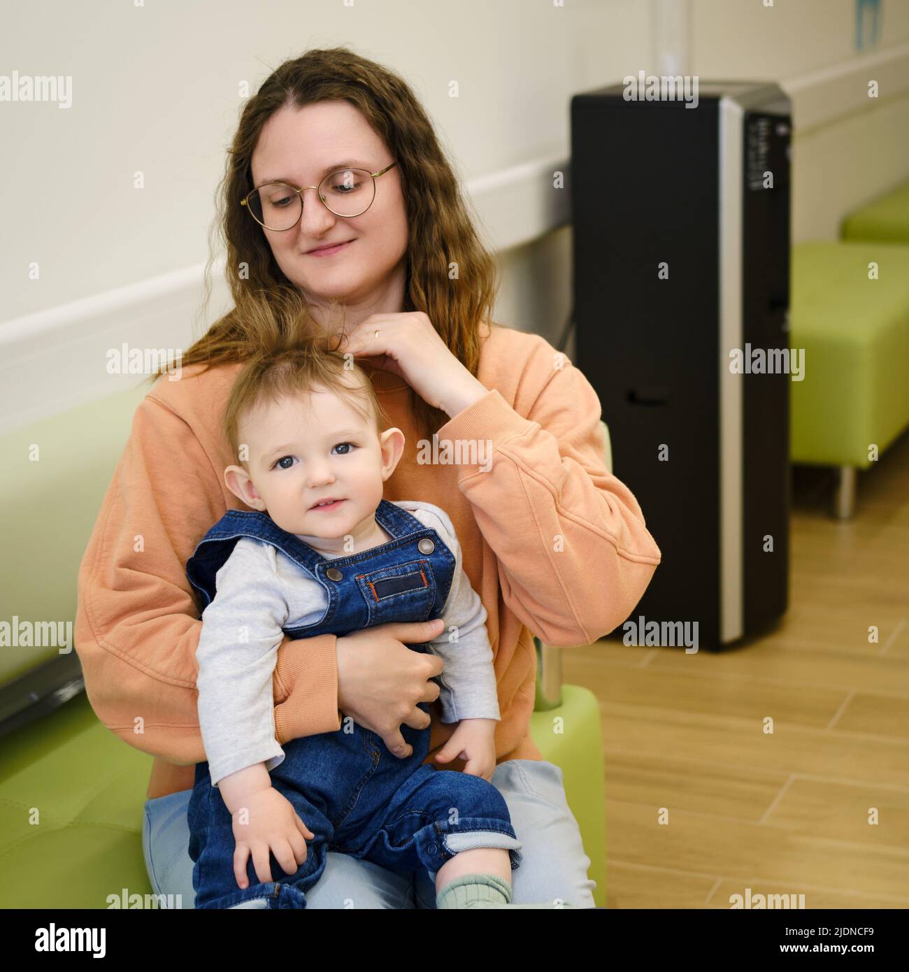 A mother woman with a toddler baby on a couch in the corridor of the ...