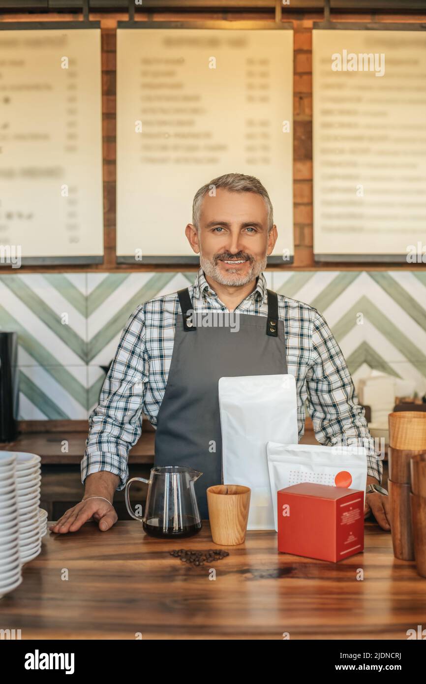 Man confidently looking at camera standing behind bar Stock Photo - Alamy