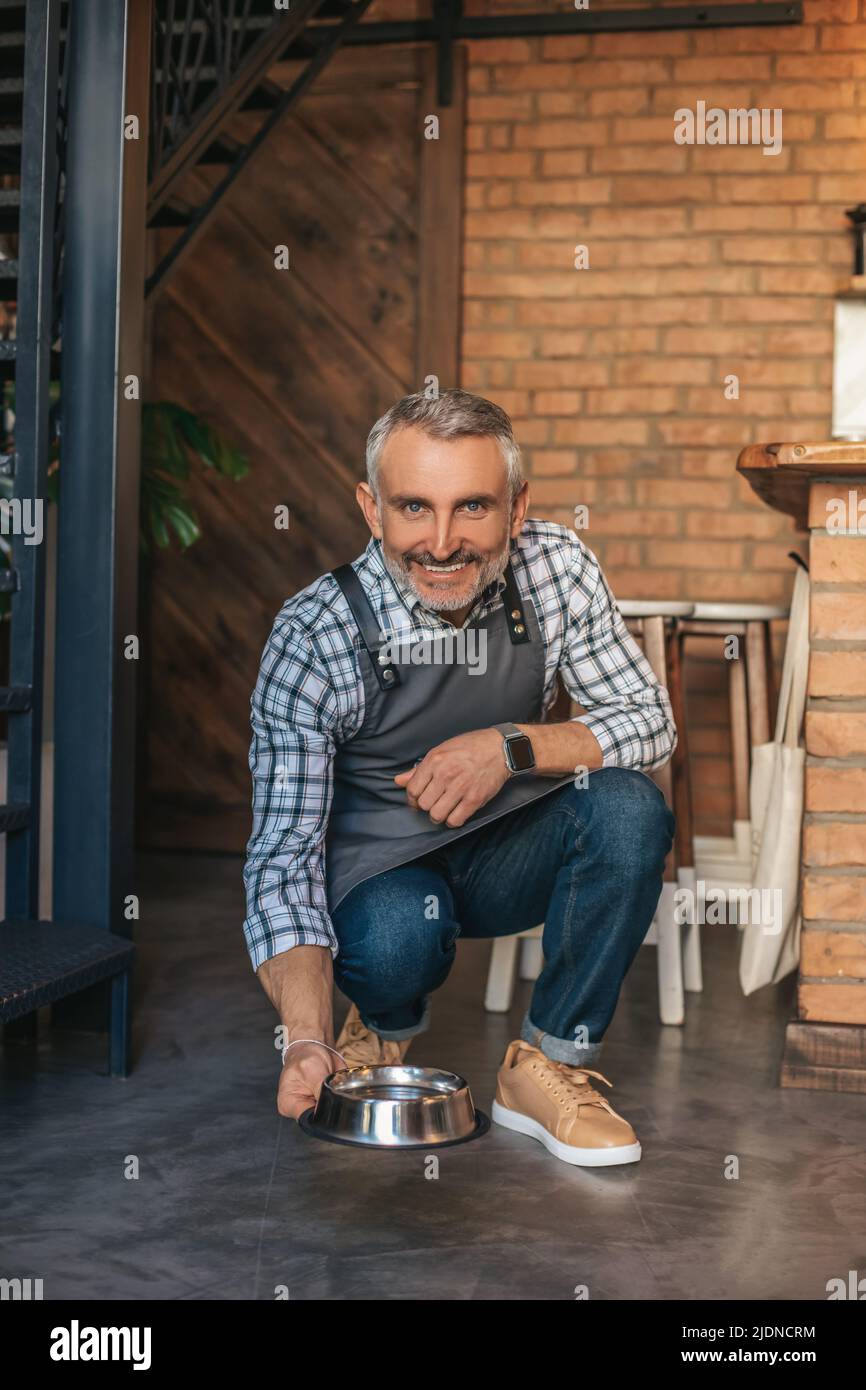 Man crouched holding out bowl of water to camera Stock Photo - Alamy